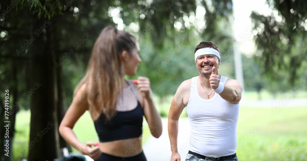Man in park shows ok gesture to sports girl. Running has beneficial ...