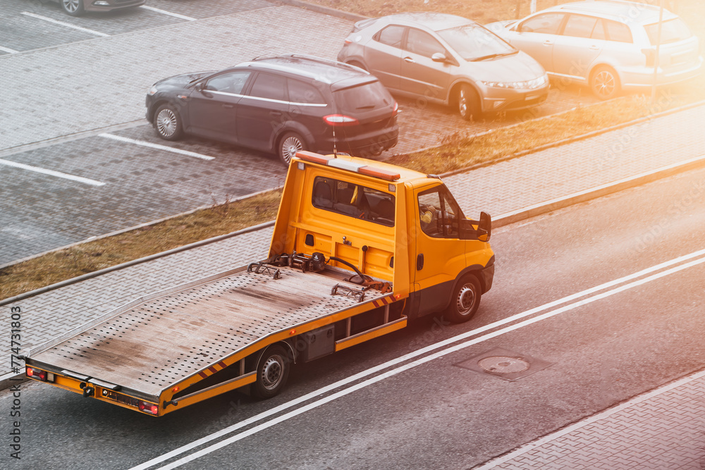 A top view from the back of an orange tow truck on a city street. The ...