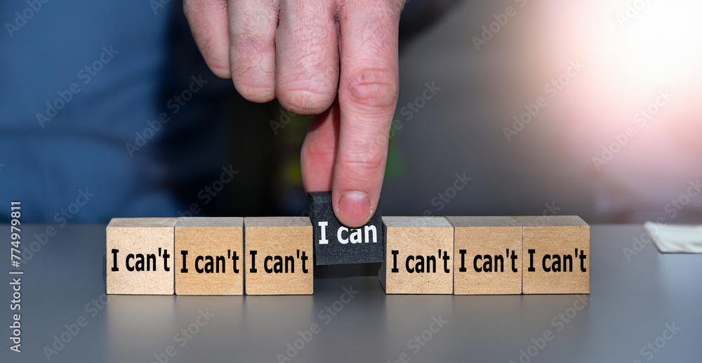 Hand picks cube with the text 'I can' instead of 'I can't. Symbol for ...
