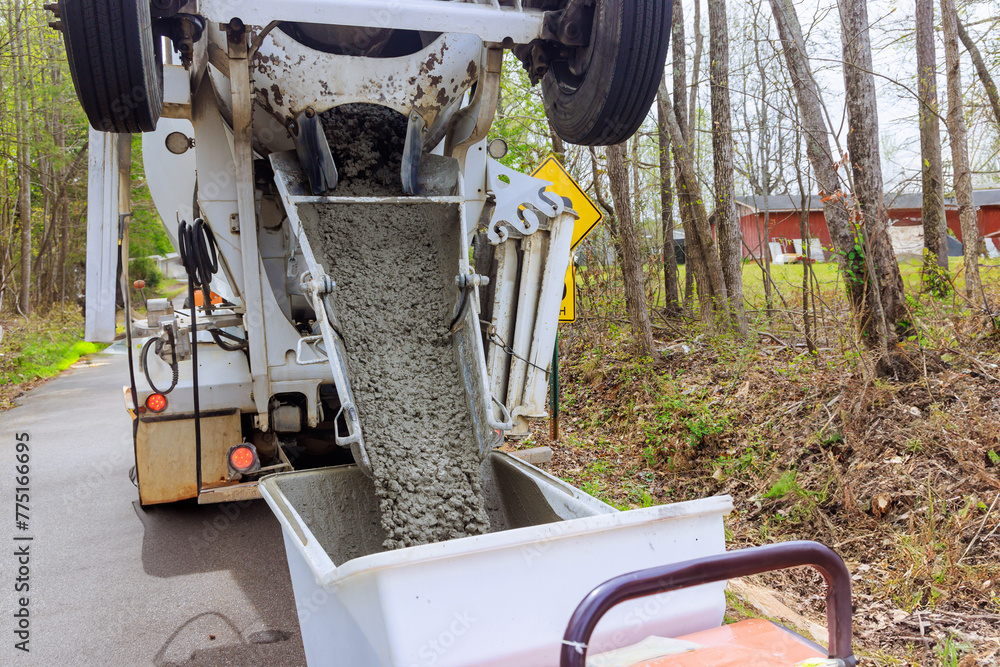 Wet cement coming down cement truck chute into a wheelbarrow track ...
