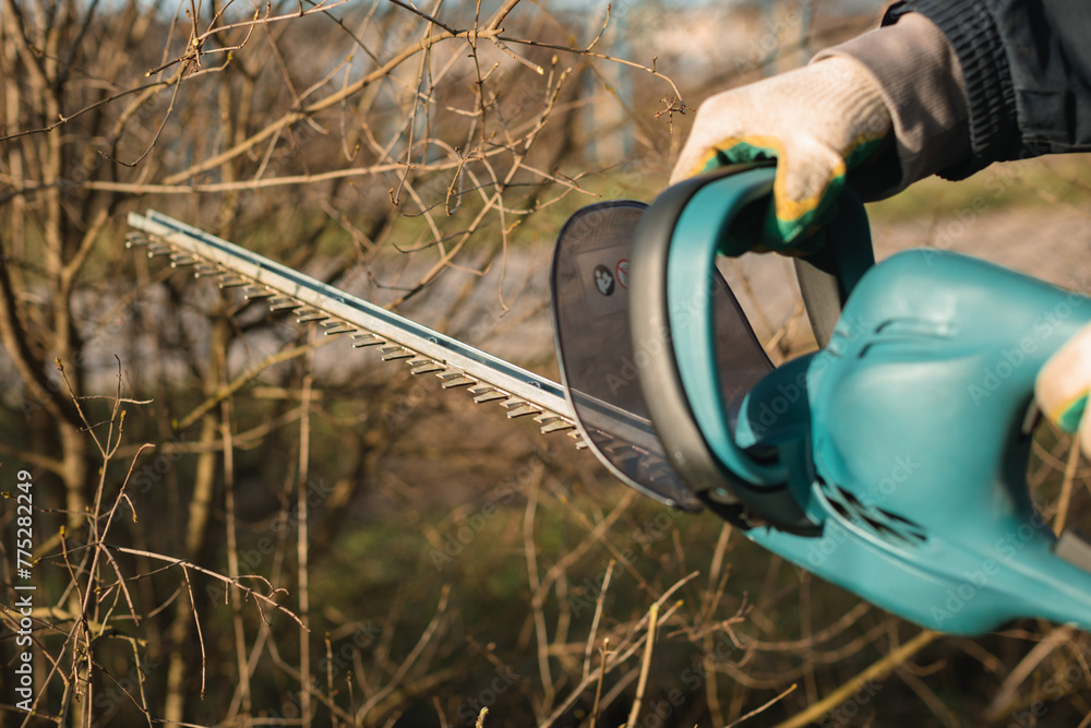 Close-up of a man using an electric brush cutter to cut off the ...