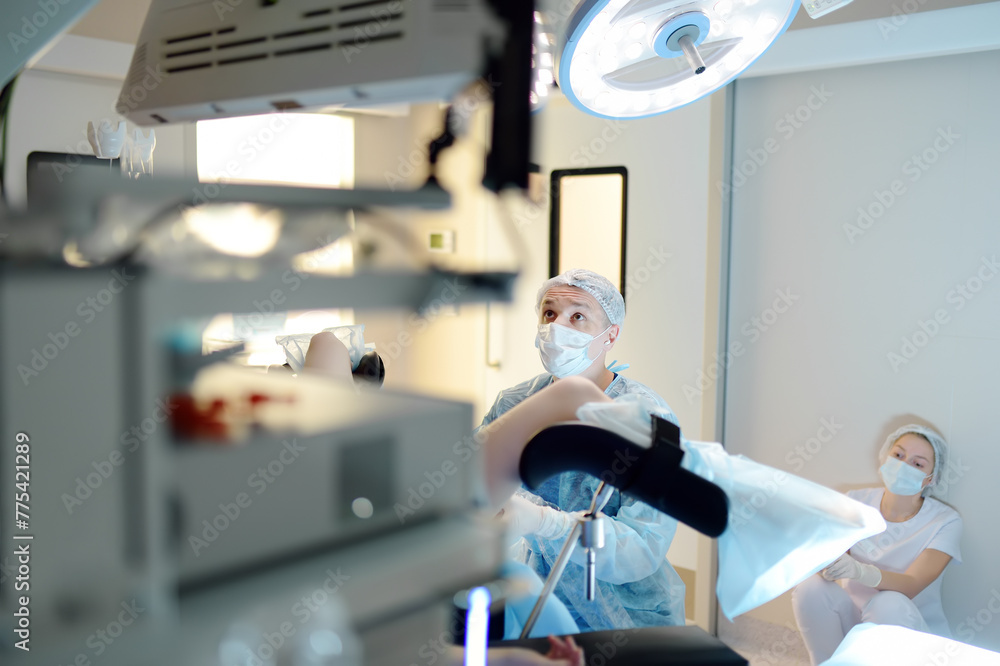 Gynecologist operating patient in gynecological chair. Doctor performs ...