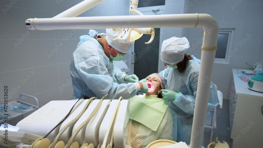 Oral surgeon, nurse doing medical operation on root canals in operating ...