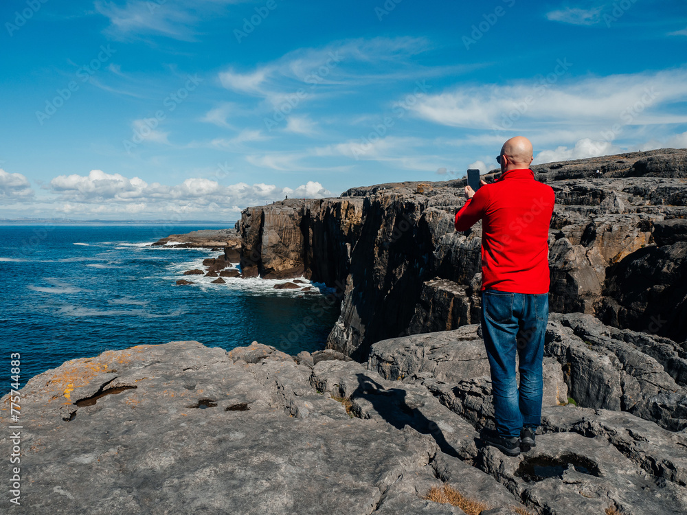 Tourist standing and enjoy view of stunning mini cliff in county Clare ...