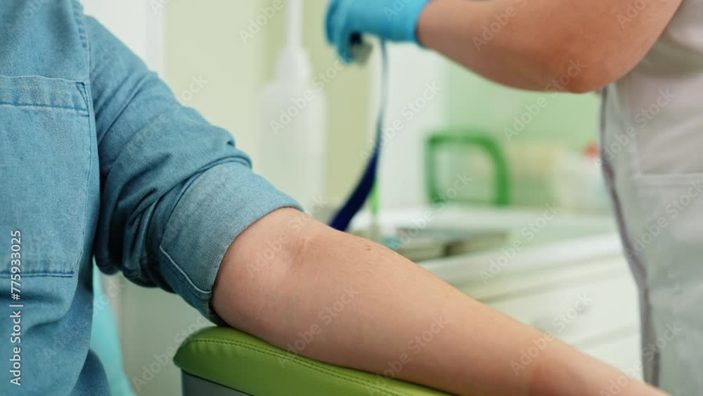 Professional female lab assistant in gloves applying tourniquet on male ...
