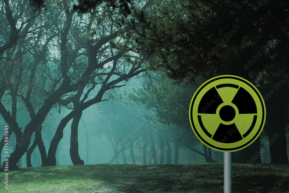 Radioactive pollution. Yellow warning sign with hazard symbol in forest ...