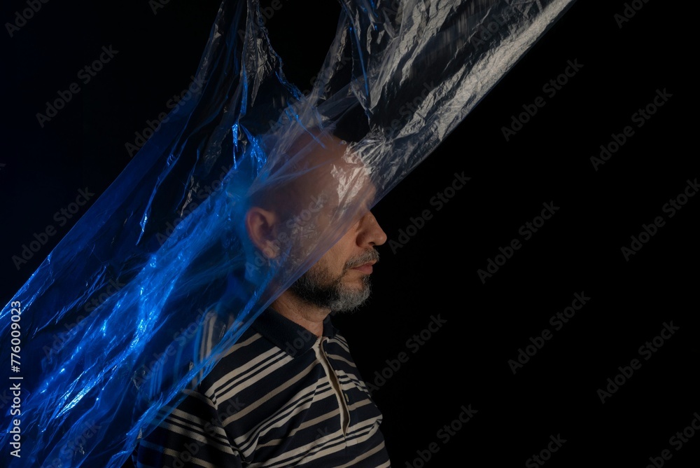 Bald mature man suffocating with a transparent plastic bag flying over ...