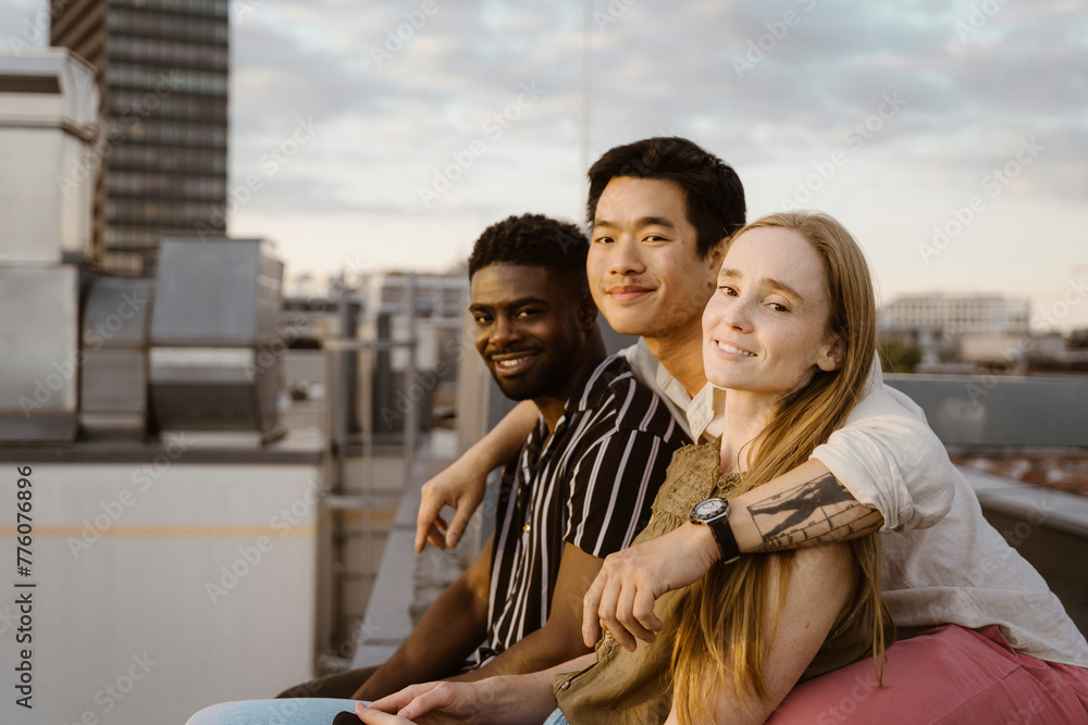 Portrait of smiling man with arms around male and female friends on ...