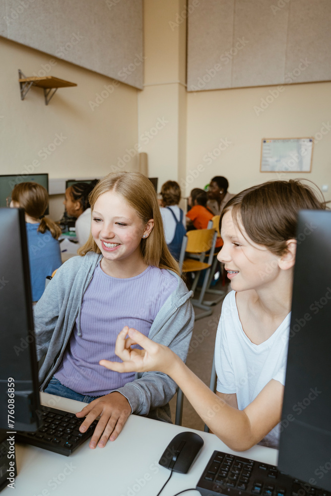 Smiling boy talking to female friend using computer while sitting in ...