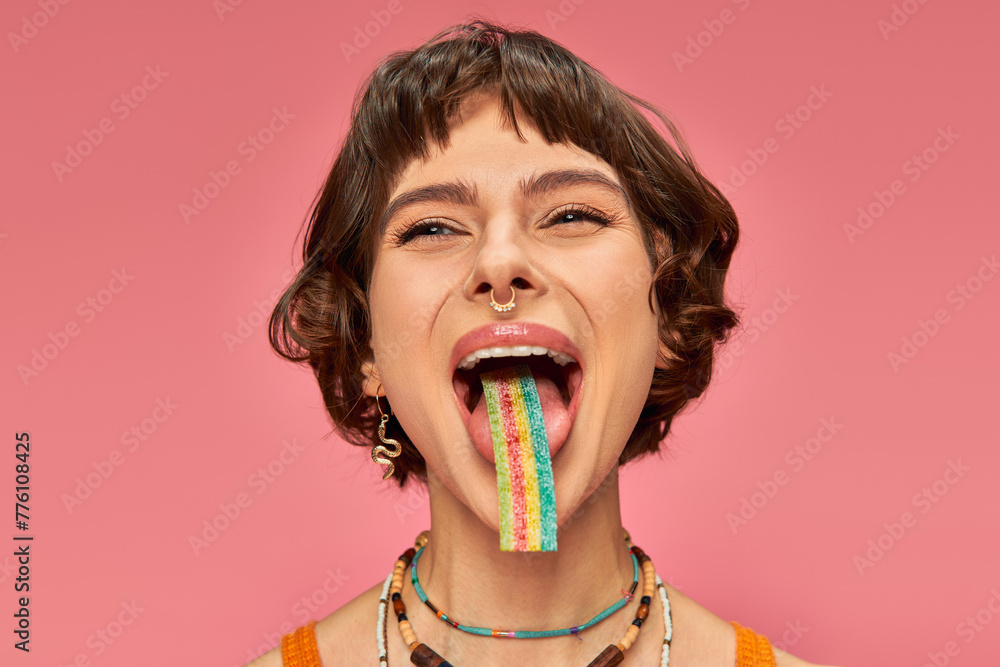 cheerful young woman in her 20s tasting sweet and sour candy strip on ...