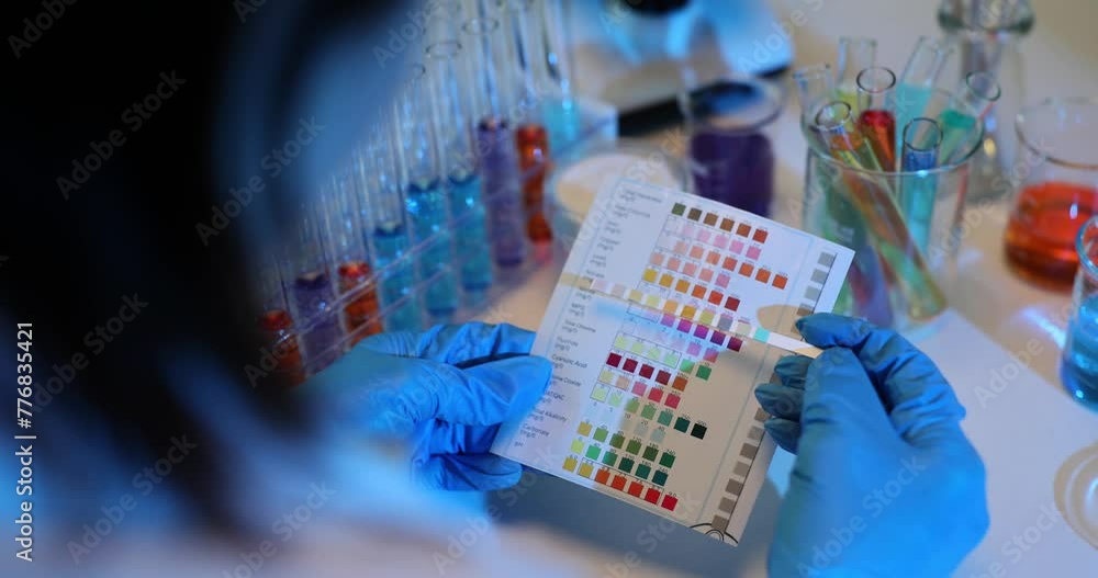 Chemist compares color-changed litmus paper with color samples in the ...