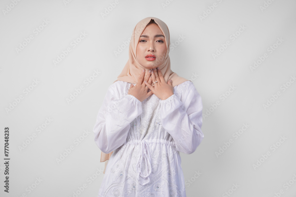 Tired Asian Muslim woman in white dress and hijab holding her neck ...