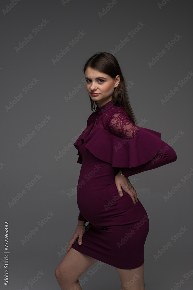 portrait of a pregnant woman in dress on a grey background, studio ...