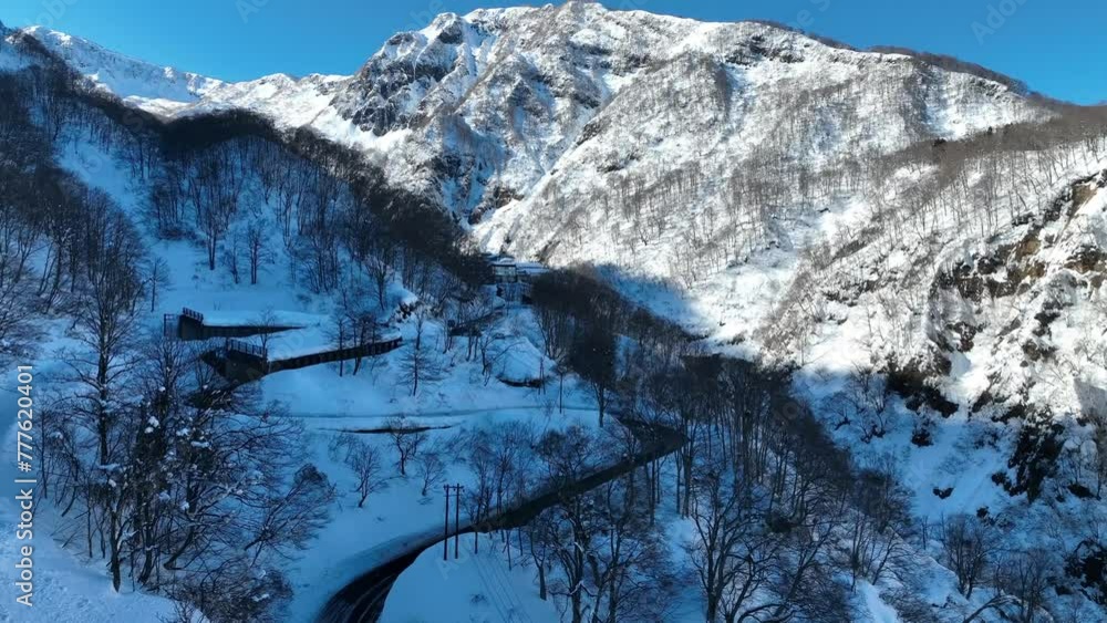 Vidéo Stock Drone shot flying above winding road at base of massive ...