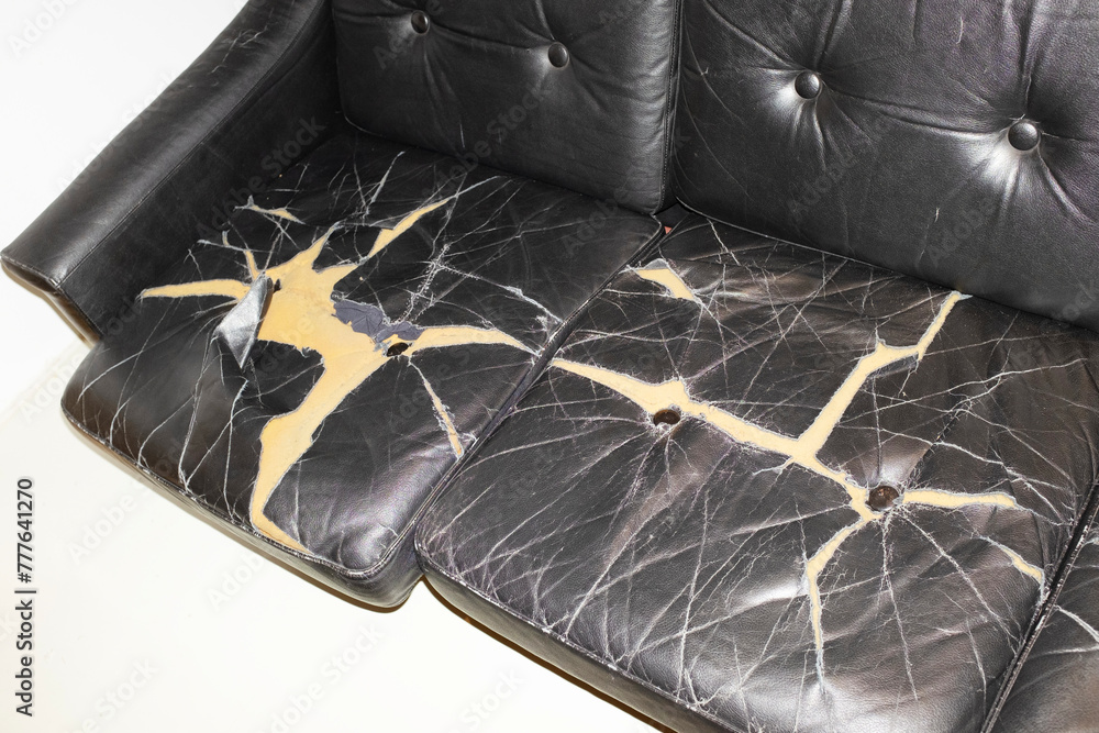 Broken leather sofa with cracks and holes with hard direct flashlight ...