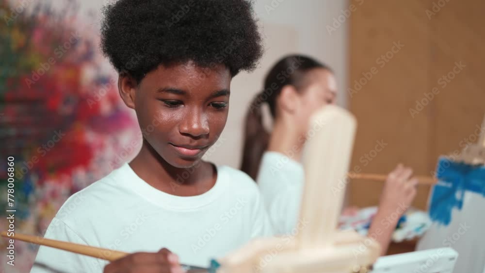 Smart african boy painting canvas while cute girl drawing behind. in ...
