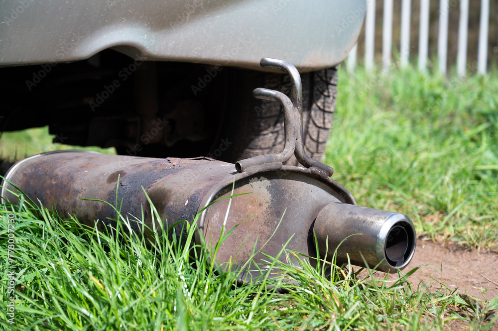 Broken exhaust and muffler of a car, rusted silencer fallen down on the ...