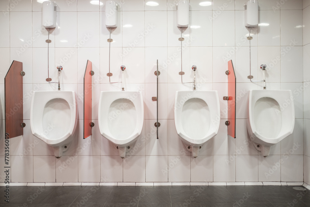 Front view of a white-walled public restroom with four symmetrical ...