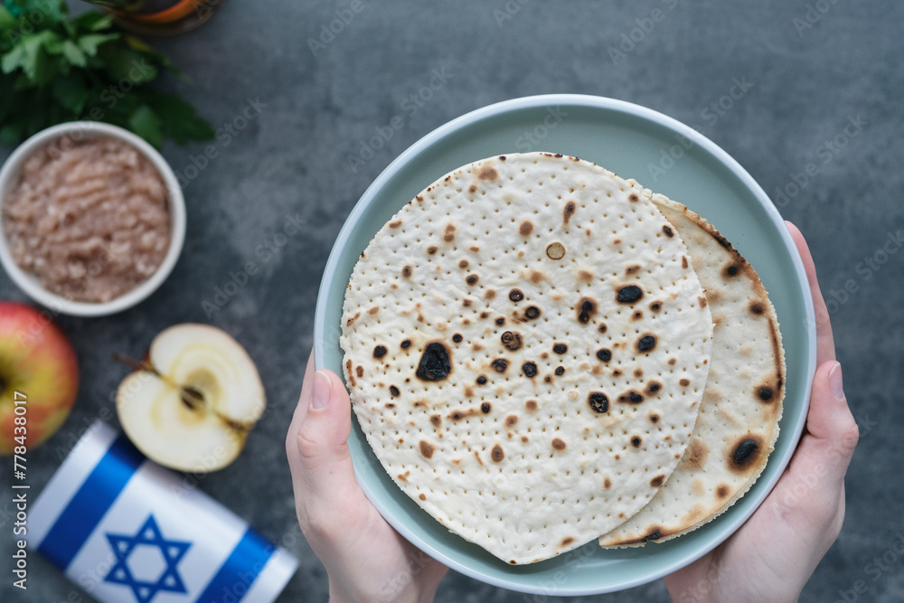 Human hands holding handmade round Matzah in a plate on a concrete ...
