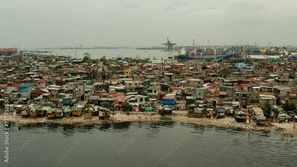 Slums in Manila near port on the bank of a river polluted with garbage ...