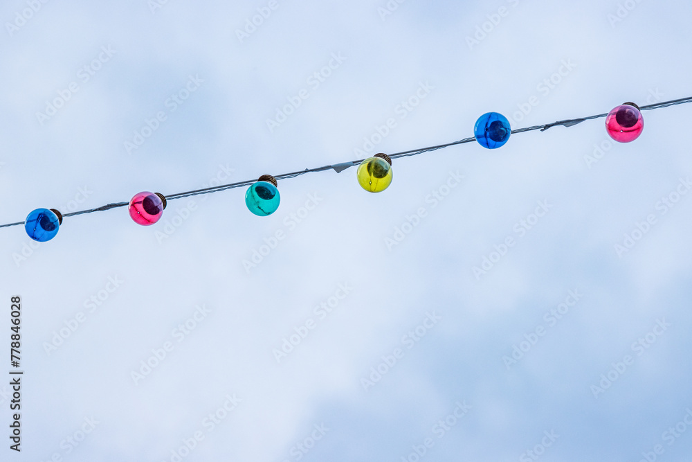 Straight line of Christm garland light bulbs on cloudy sky background ...