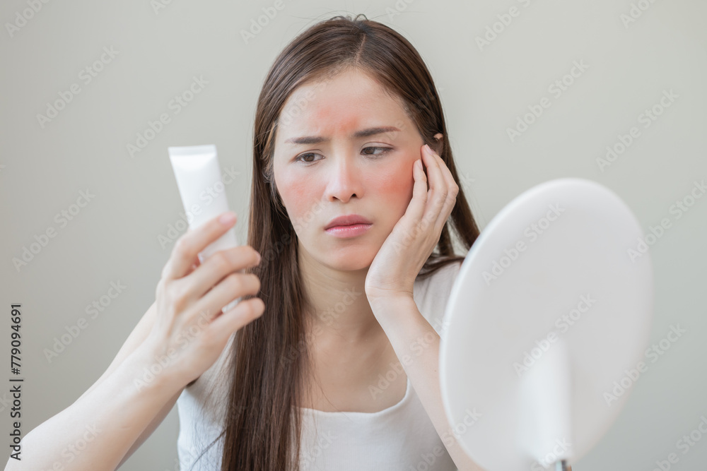 Dermatology, asian young woman looking at mirror, holding cream tube in ...