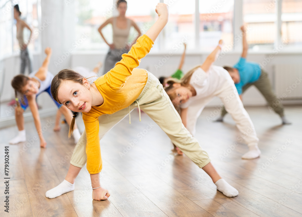 Group of focused tween children standing akimbo in row one by one ...