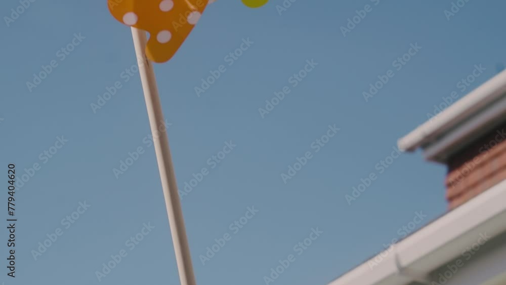 Camera panning up from a childs hand to a bright happy windmill spinner ...