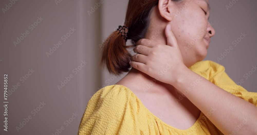 A young woman is pinching her nape as she massages it to relieve ...