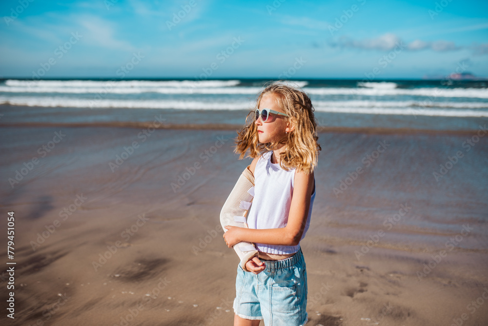 Foto de Girl with broken arm on beach. Young blonde girl has arm cast ...