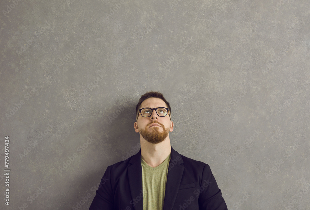 Serious caucasian man with a pensive and dubious expression looks up ...