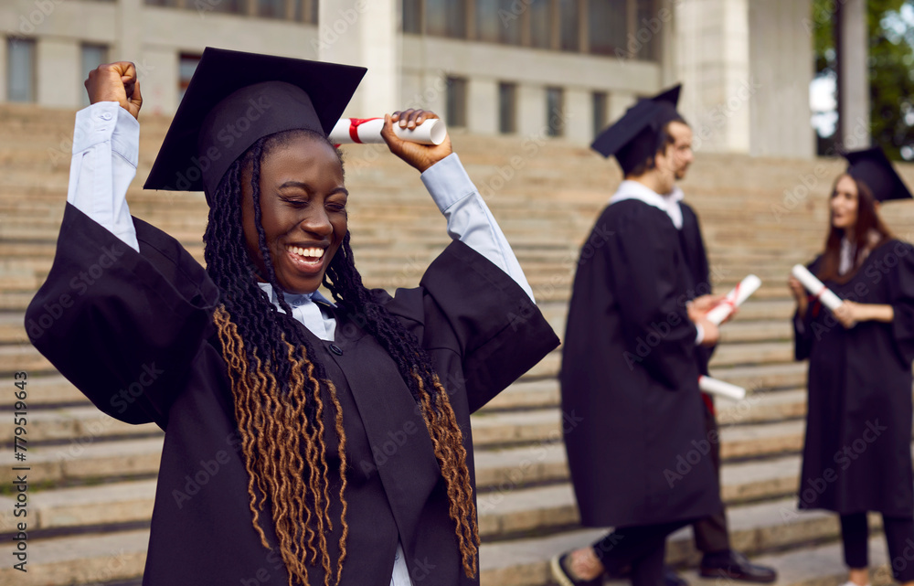 Young smiling excited african american student in a university gown and ...