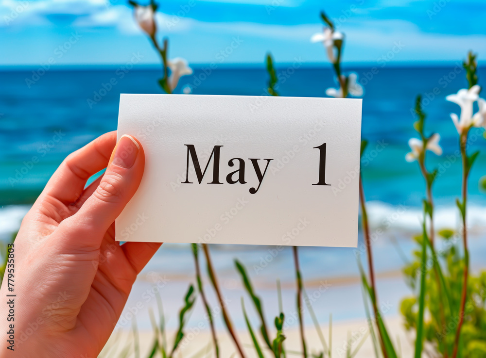 Hand holding a card MAY 1, concept of the first day in may and ...