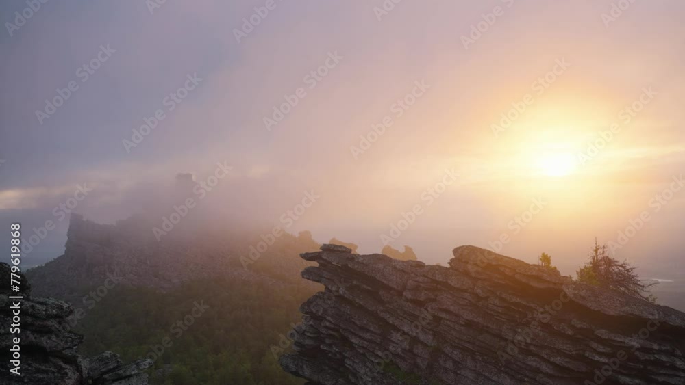 The early morning sun breaks through the mist, illuminating the layered ...