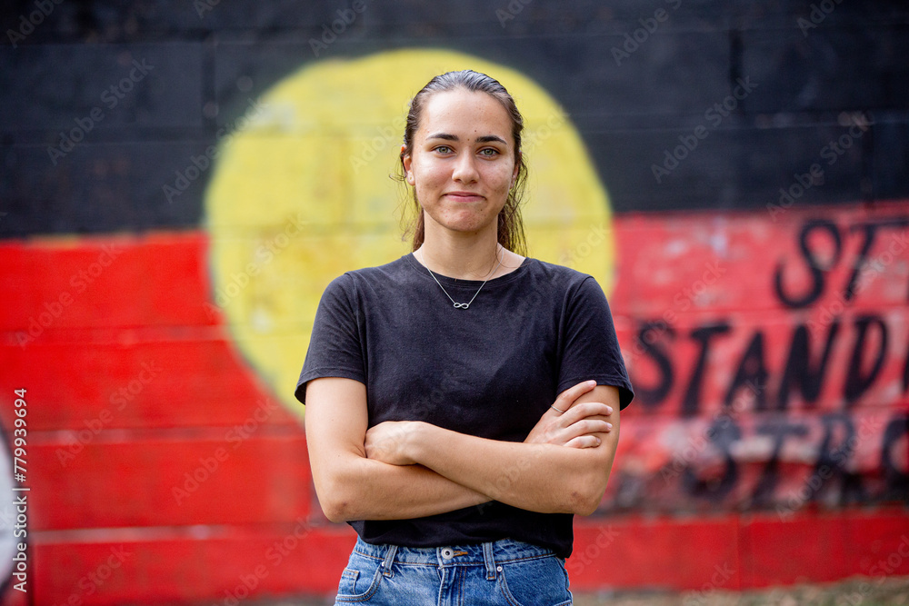 20-something Aboriginal woman standing with her arms crossed in front ...
