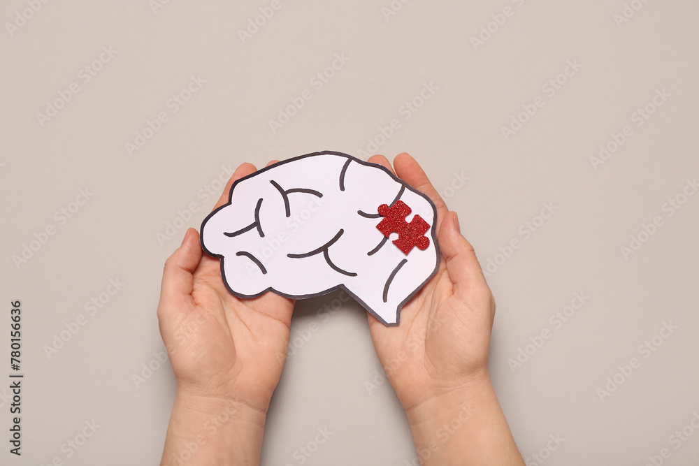 Female hands with paper brain and puzzle piece on grey background ...