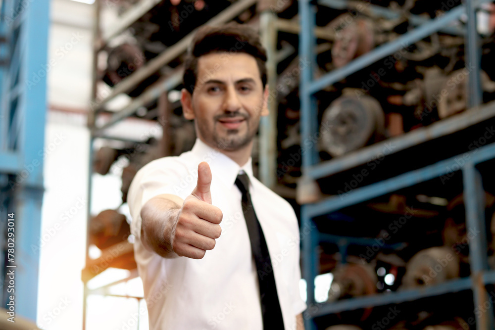 Businessman giving thump up to camera at auto spare parts store ...