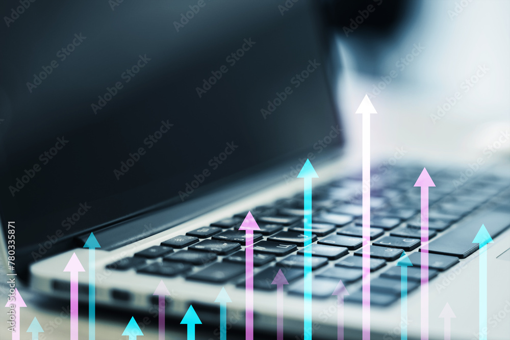 Close up of laptop on desk with various growing arrows on blurry ...