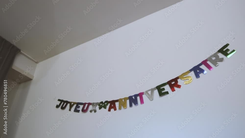 A slow tilt down reveals French text Joyeux Anniversaire on the wall ...