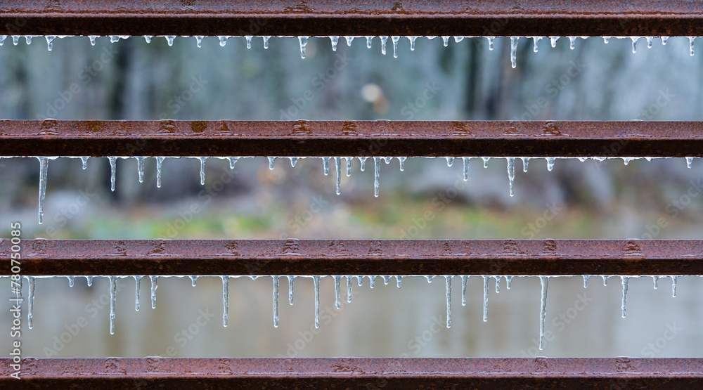 Horizontal, rusted, iron bars in fence covered in thick ice from a ...