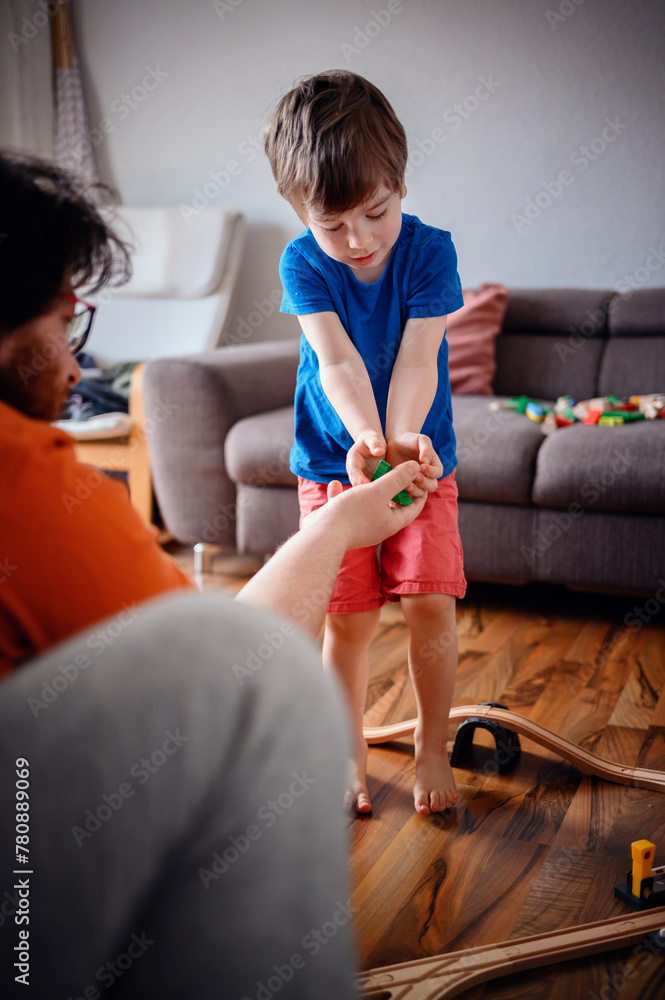 A child interacts with an adult while playing with a toy train ...