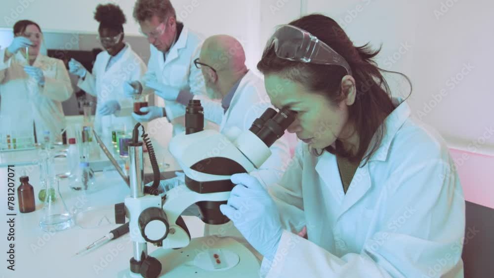 Japanese scientist using a microscope in a multicultural laboratory ...