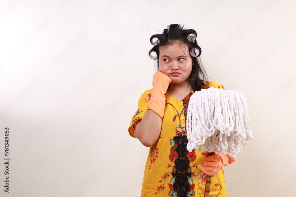 Sad Asian woman housekeeper standing holding a mop while looking ...