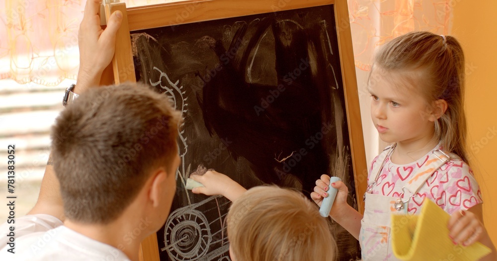 Family is drawing with chalk on chalkboard. Mother, father, and two ...