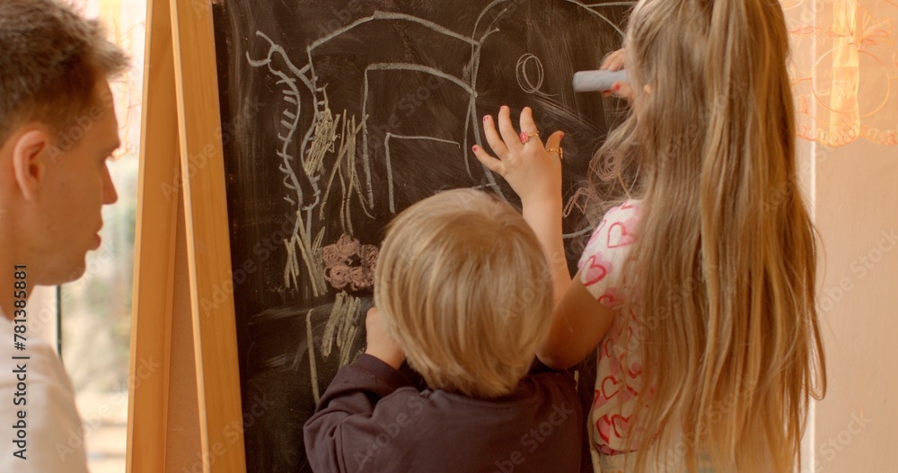 Kids drawing spider with chalk on black chalkboard at home. Learning ...