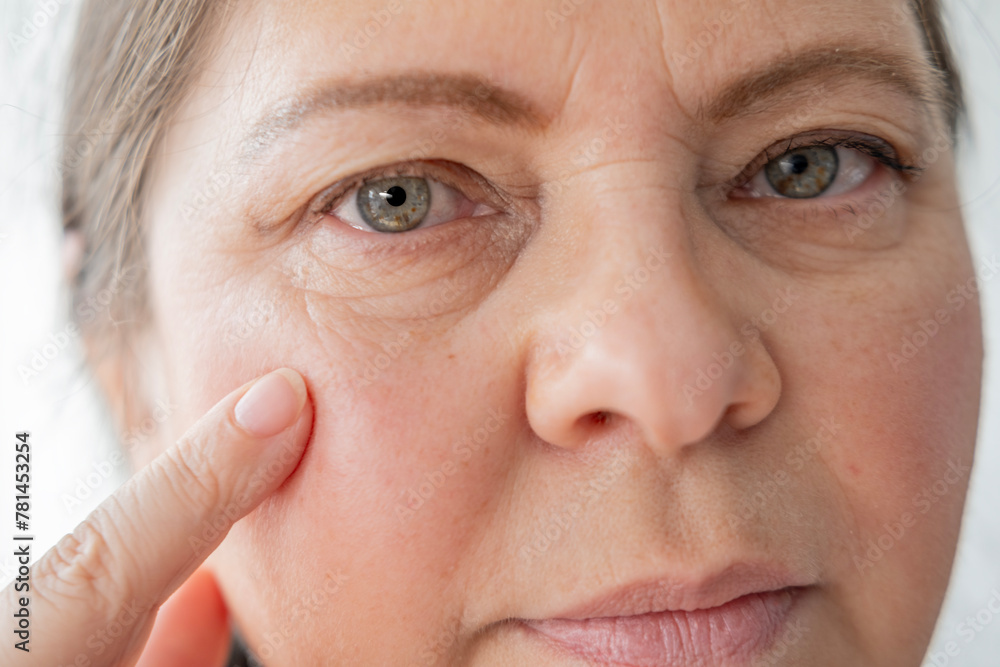 close up mature female face, aging woman 55 years old gazes herself in ...