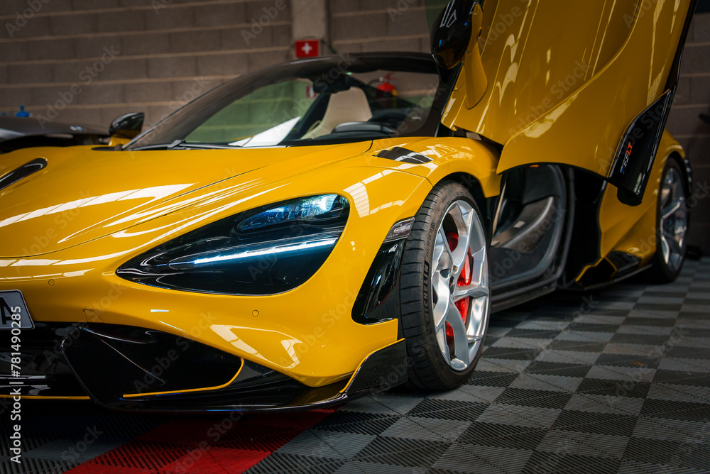 A bright yellow McLaren 765LT, with dihedral doors, is in a tuning ...