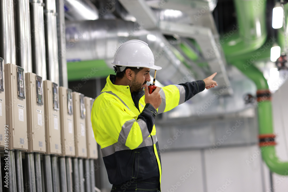 Mechanical engineer with green safety jacket holding laptop and walkie ...
