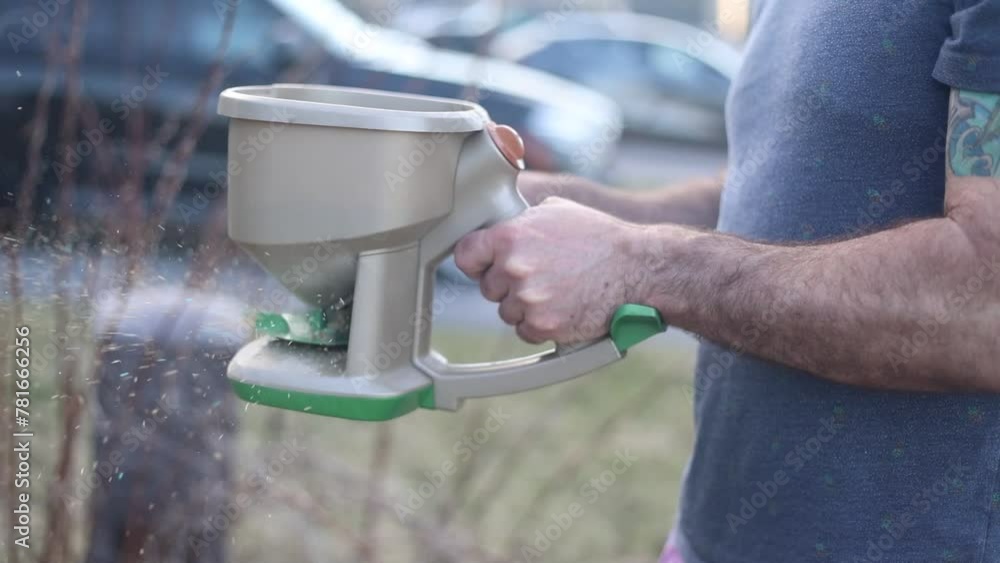 Man Fertilizing Lawn with Handheld Spreader. Close-up of a man's hands ...
