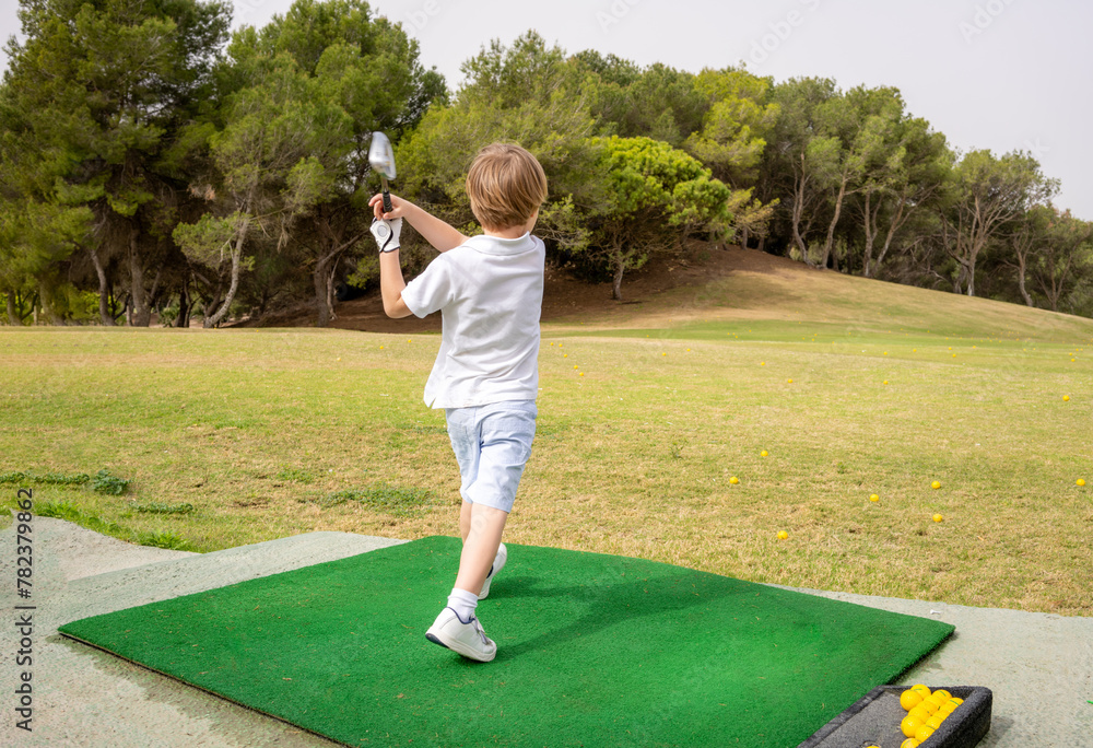 Little boy on on golf course looking after the golf ball in a shot ...